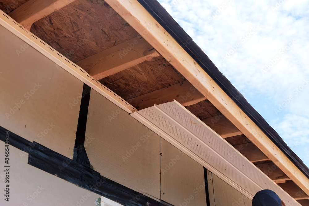 Installation polyvinyl soffit at roof corners of house with rafters ...