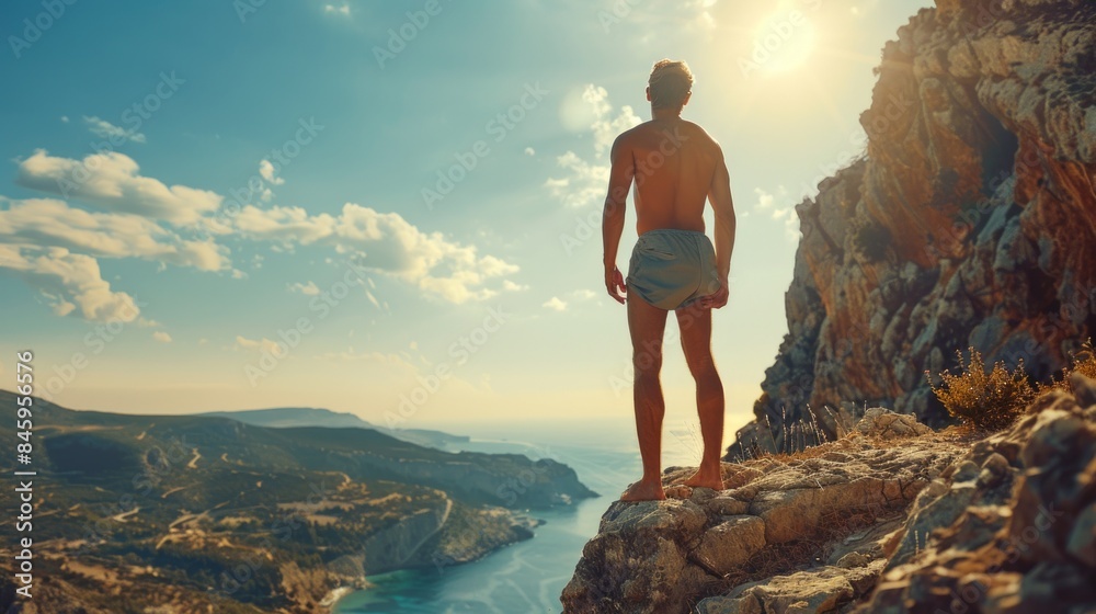 Back view of a fit, shirtless man enjoying a stunning mountain sunset ...