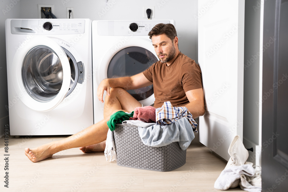 Happy man sorting clothes near washing machine in laundry room. man ...