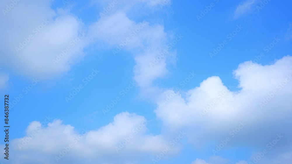 A serene day under a clear, soft blue sky, as white clouds drift ...