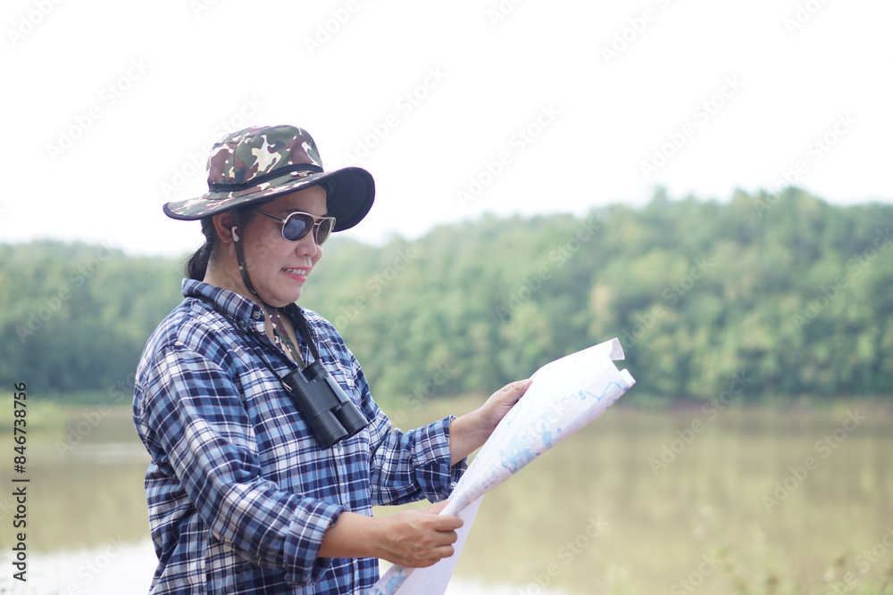 Asian woman exploror is looking at paper map to explore nature at the ...