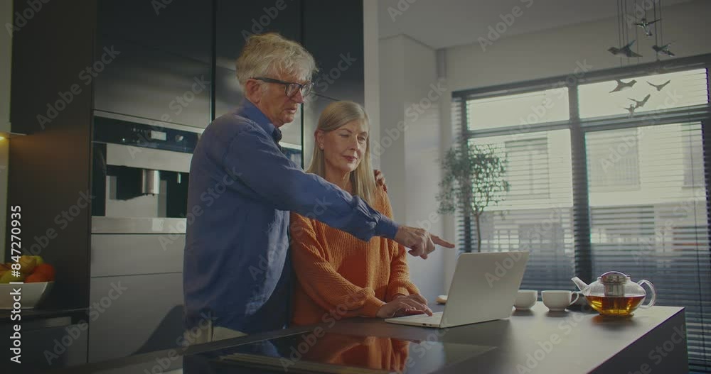 Older Caucasian couple standing together in middle of modern kitchen ...