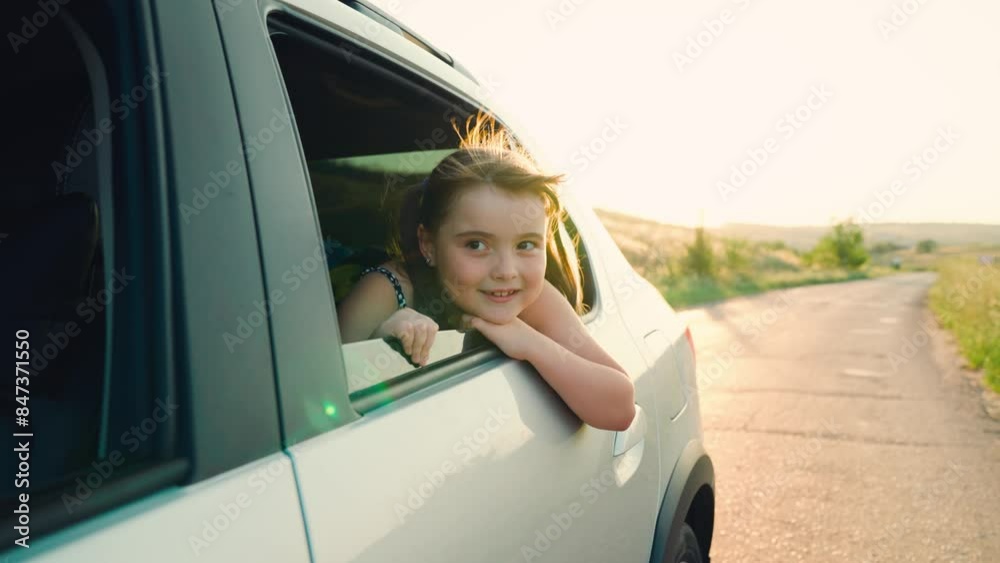 child girl face looks smiling from car out window, sunlight countryside ...