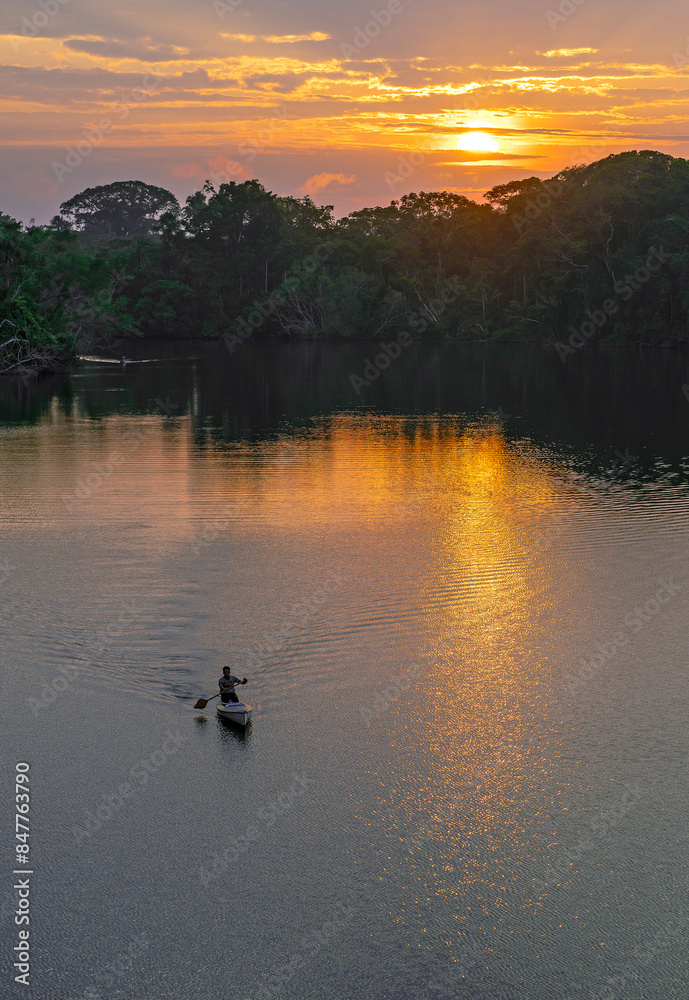 Native Quechua man paddling his canoe at sunrise, Amazon jungle, Yasuni ...