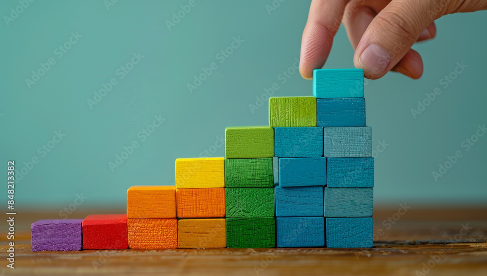 Hand placing wooden blocks in ascending order to form a colorful staircase Stock Photo | Adobe Stock