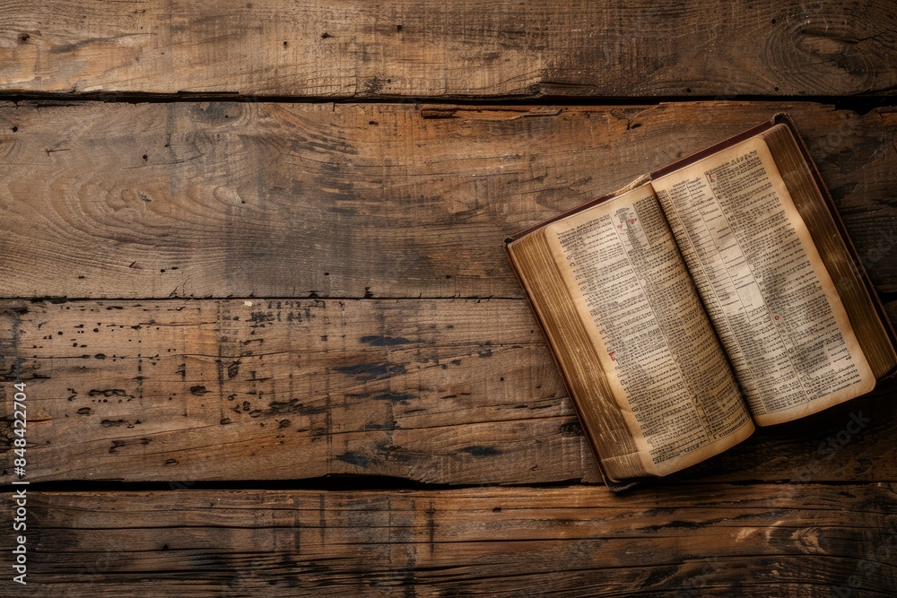 An open Bible rests on a rustic wooden table. The pages of the book are ...