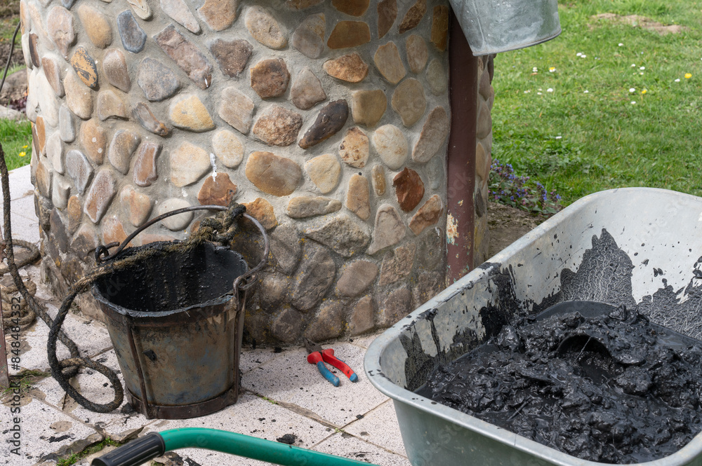 Silt from the bottom of a well in a bucket and a wheelbarrow. Stock ...