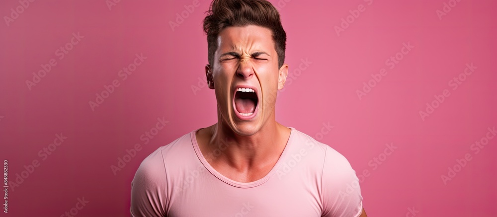 Young emotional man on a pink studio backdrop portraying hate rage and ...