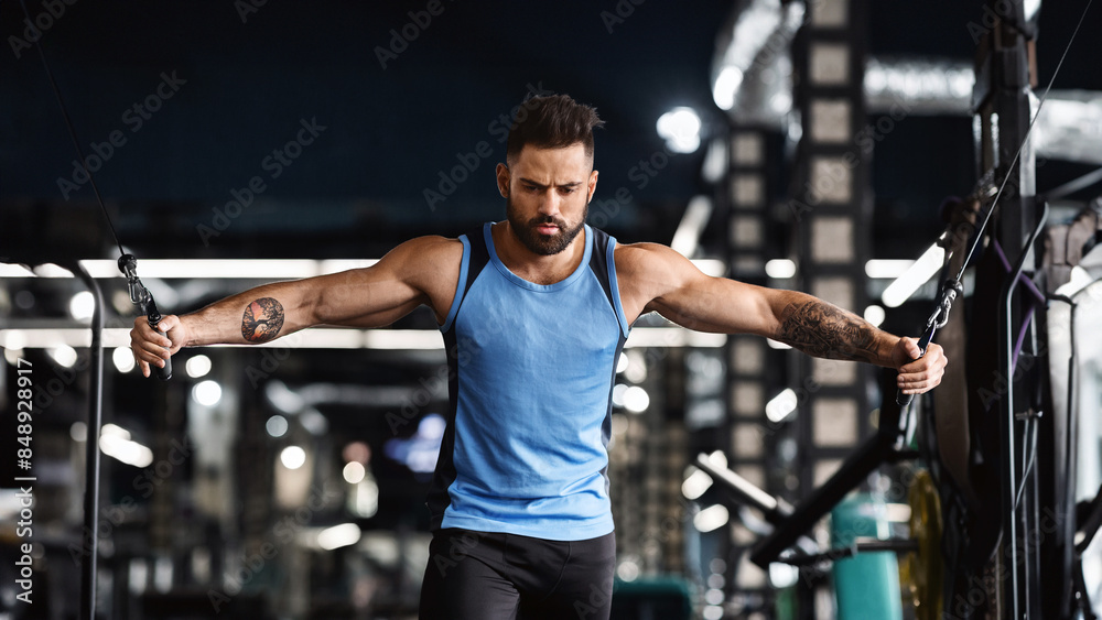 Handsome focused bodybuilder working out pushing up exercise in gym ...