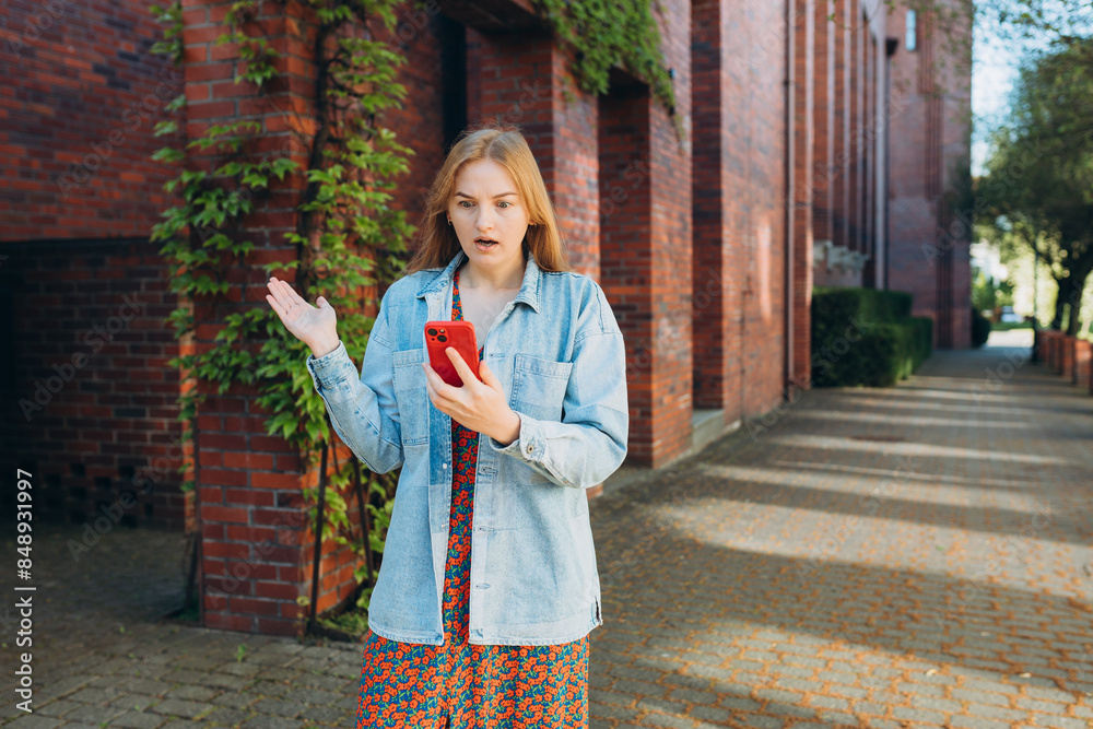 Sad angry girl in shirt with phone standing on city street. Negative ...
