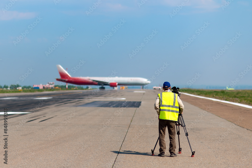 Airliner at the airfield. A man shoots a passenger plane with a camera ...