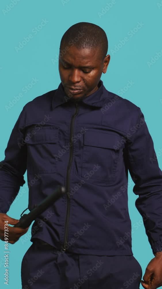 Vertical video Security guard removing baton from belt, preparing to ...