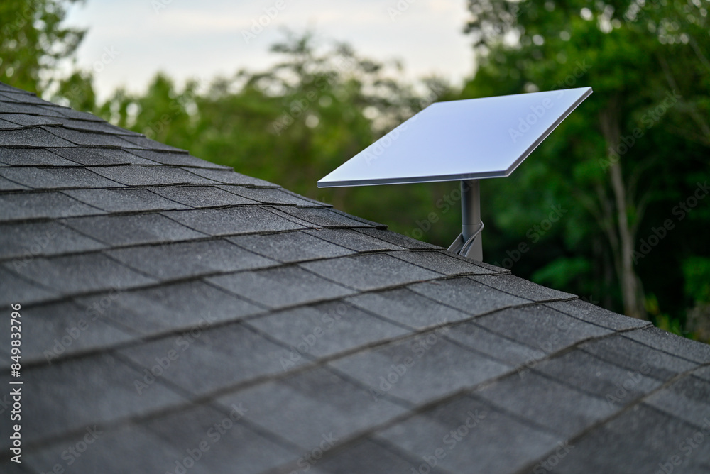 Starlink satellite dish with a wall mount on a shingle roof. Shot on ...