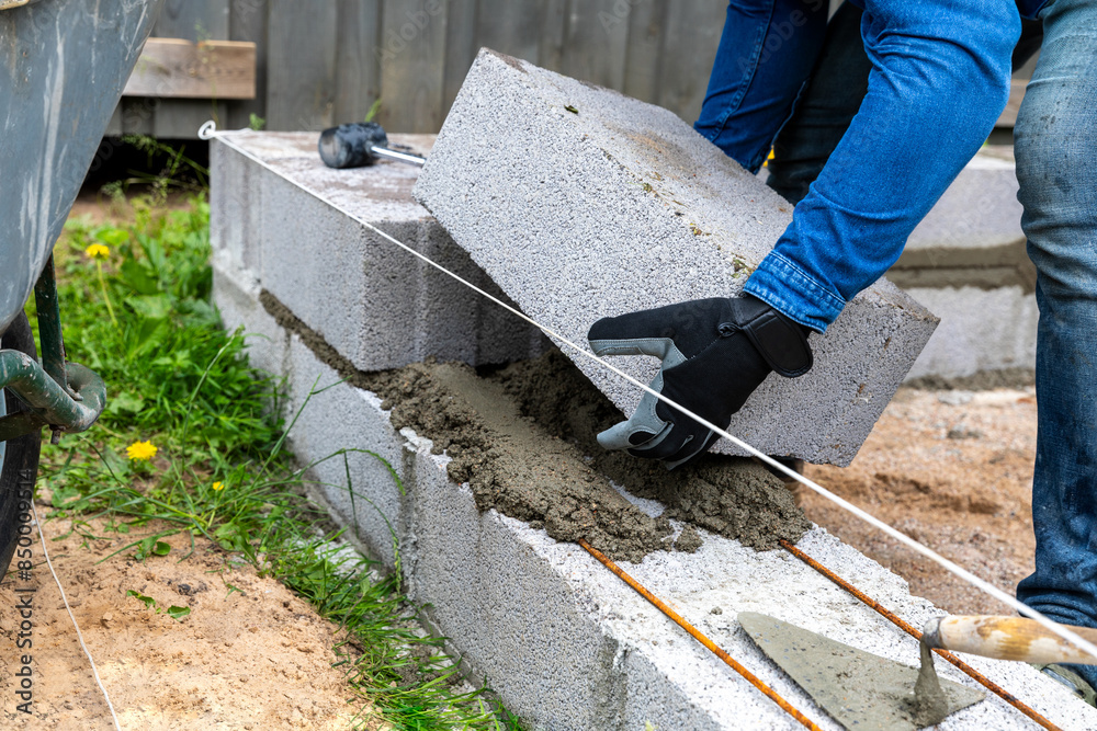 Construction worker laying expanded clay blocks. Foundations of a house ...