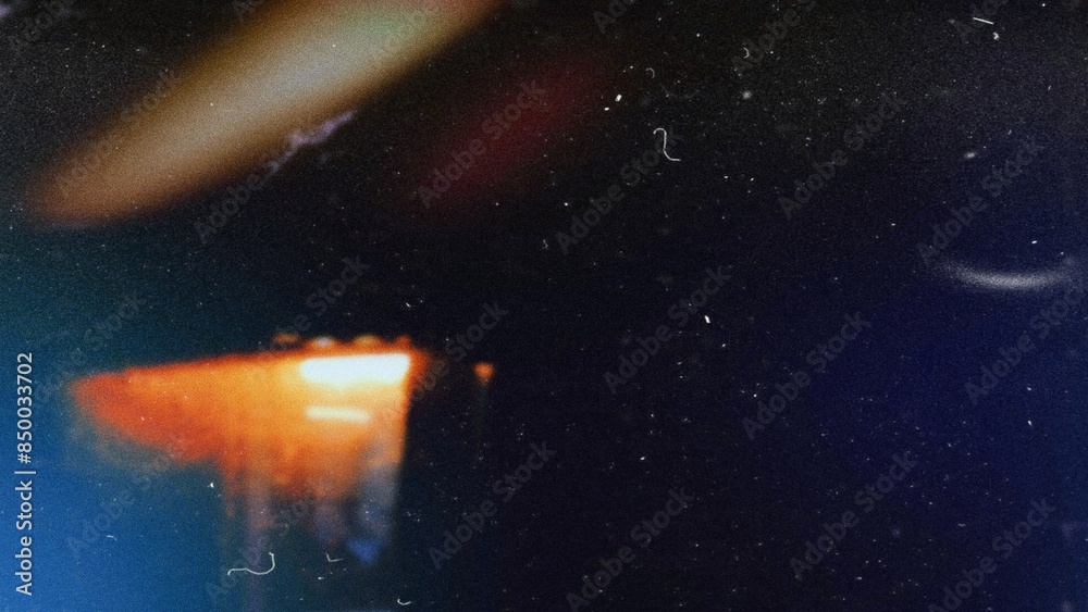 grainy colorful warm blue light leaks on black background with dust ...