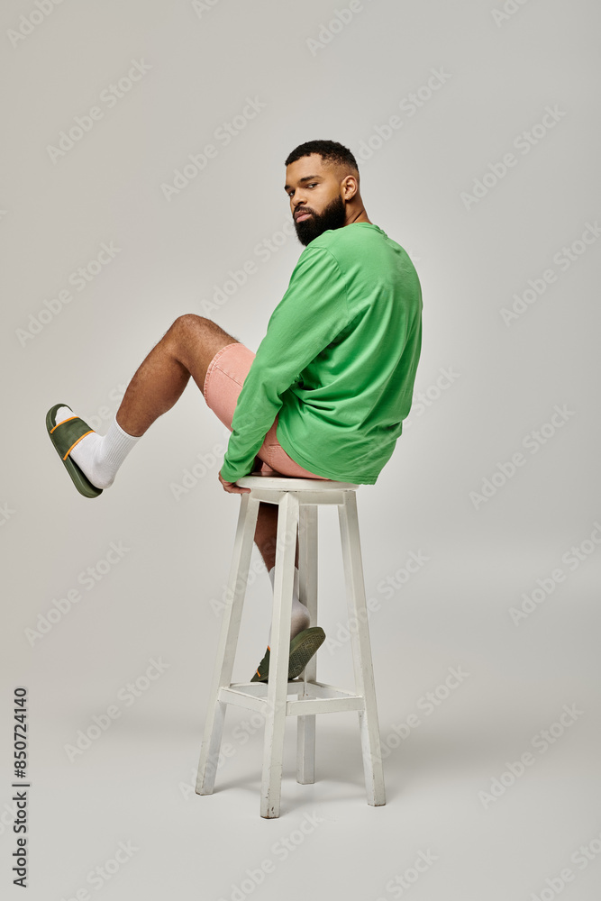 Handsome African American male striking a pose on a white stool against ...