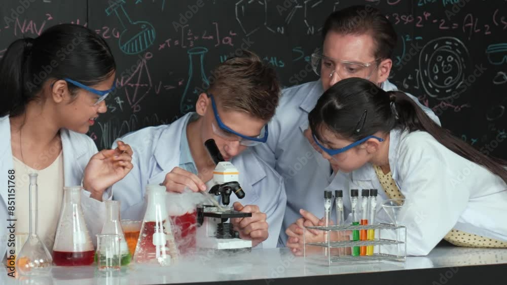 Multicultural student looking under microscope while cute girl inspect ...