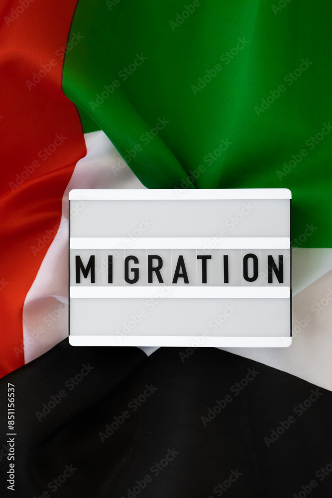 Message MIGRATION on background of UAE flag made from silk. United Arab ...
