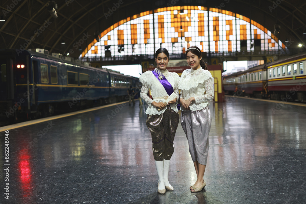 Two attractive women in traditional Thai dress pose for a photo with a ...