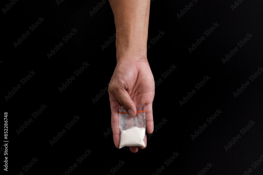 Hand giving cocaine in plastic package isolated on black background ...