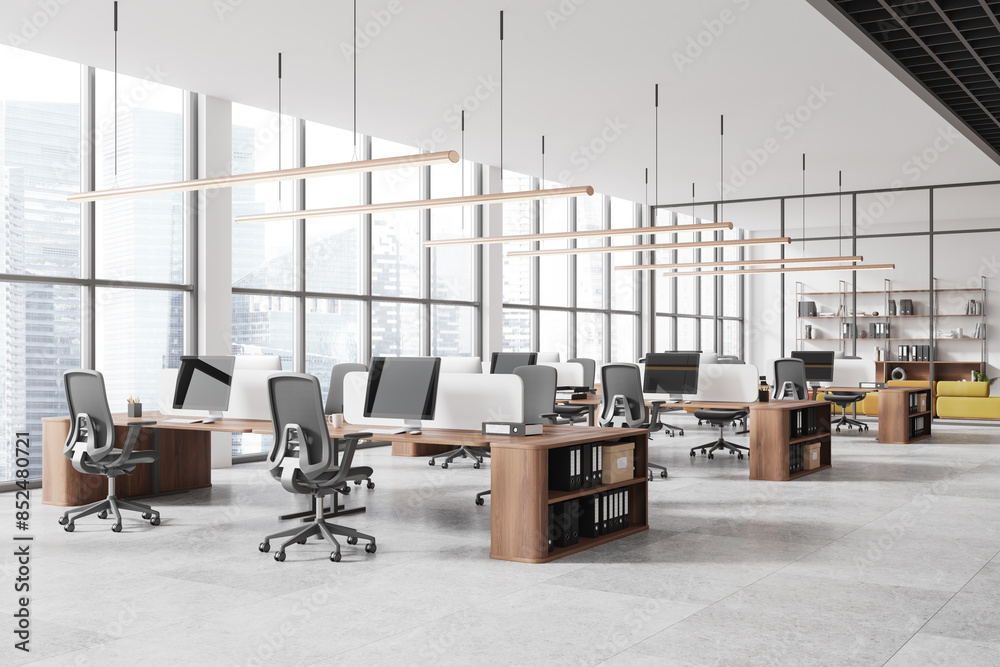 Modern open-plan office with desks and computers, large windows with ...