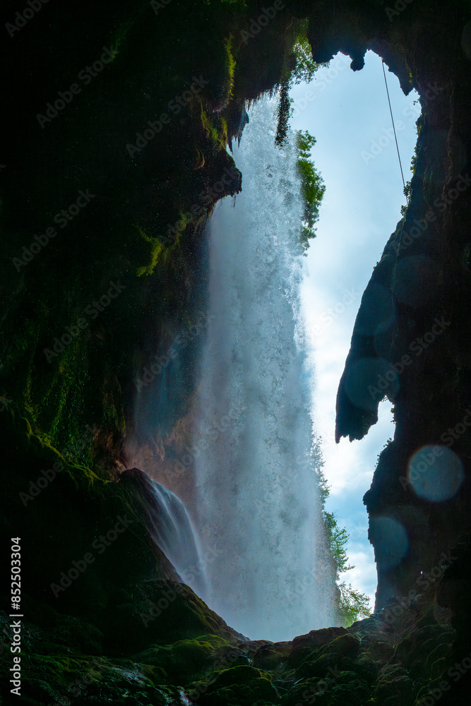Inside the waterfall in the Iris Grotto at the Cola de Caballo ...