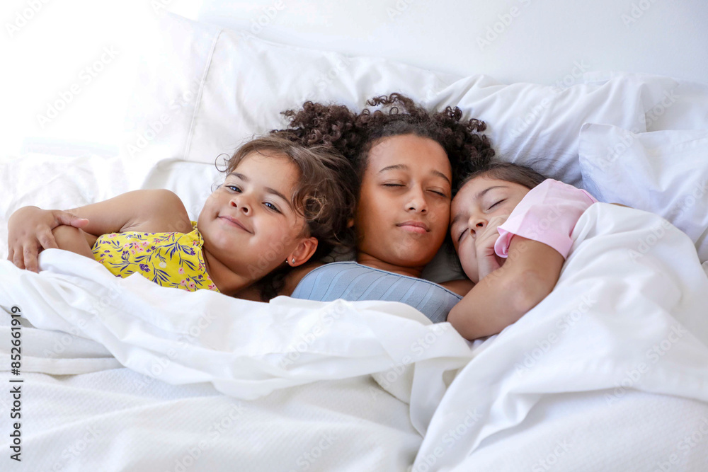 Multiethnic siblings snuggle up in bed after waking Stock Photo | Adobe Stock