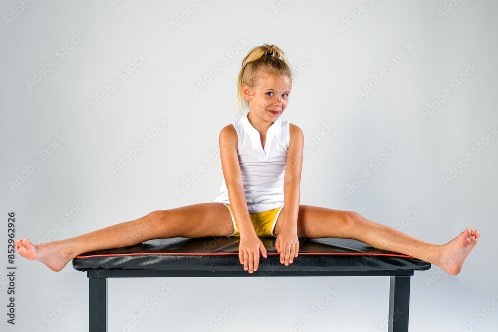 Confidently smiling young female gymnast or dancer doing splits on a ...