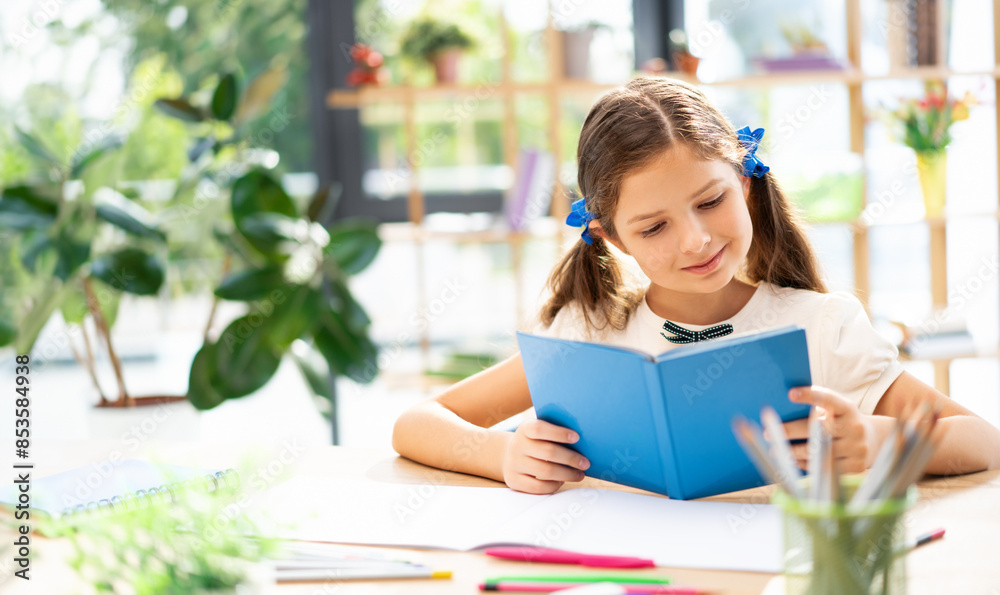 Portrait of pretty little schoolgirl sit at table desk, read textbook book, ready to study ...