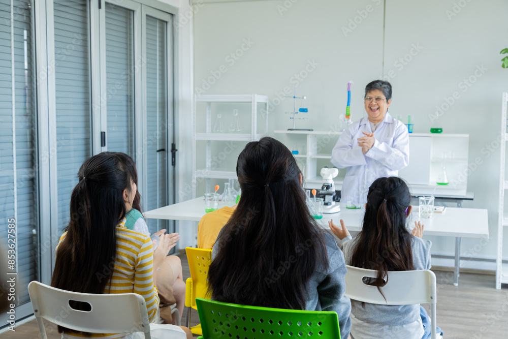 Senior teacher woman demonstrating microscope experiment to students in ...