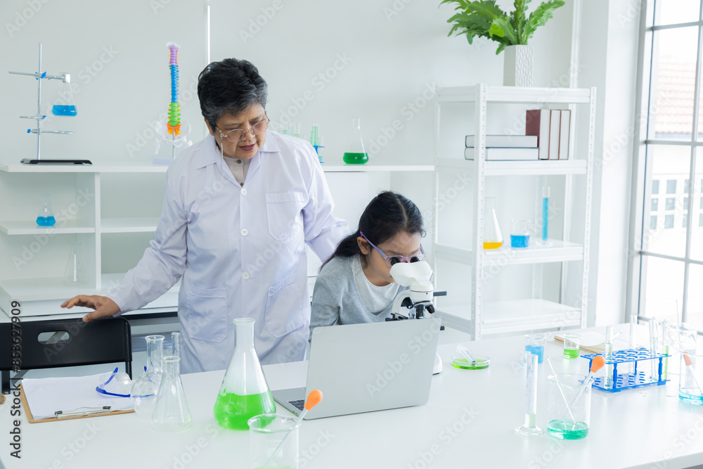 Senior teacher woman demonstrating microscope experiment to students in ...