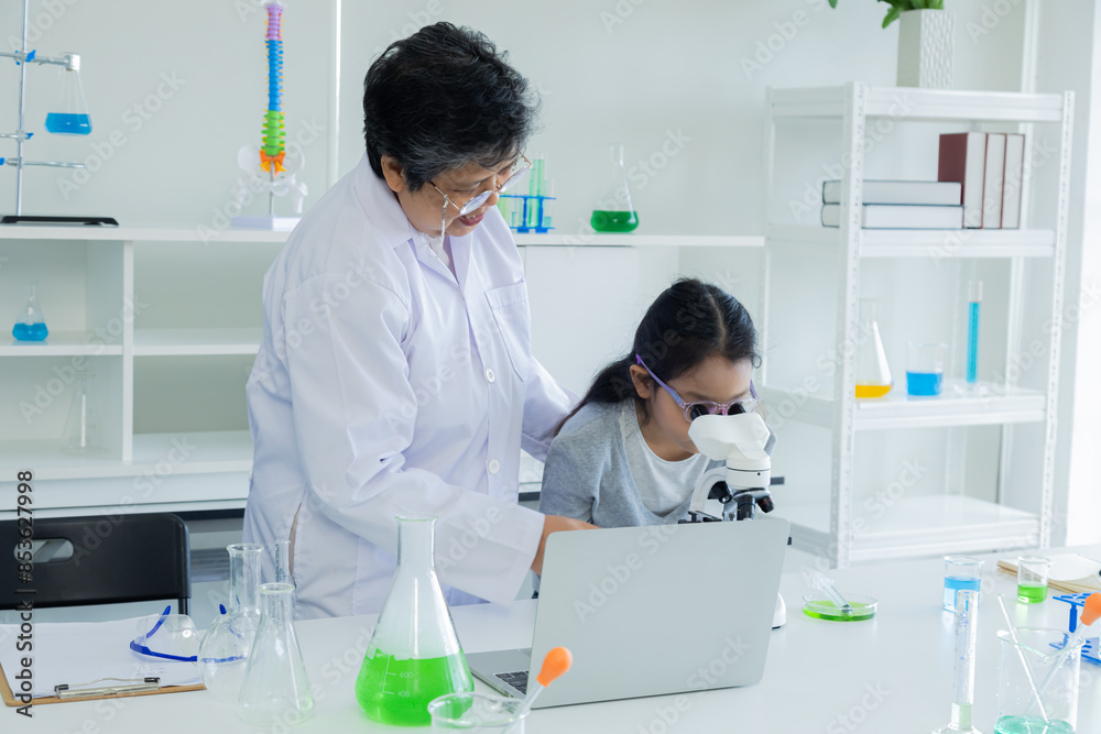 Senior teacher woman demonstrating microscope experiment to students in ...