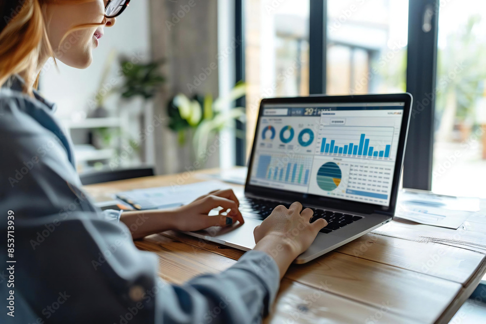 Female financial data analyst utilizing a KPI dashboard on her laptop ...