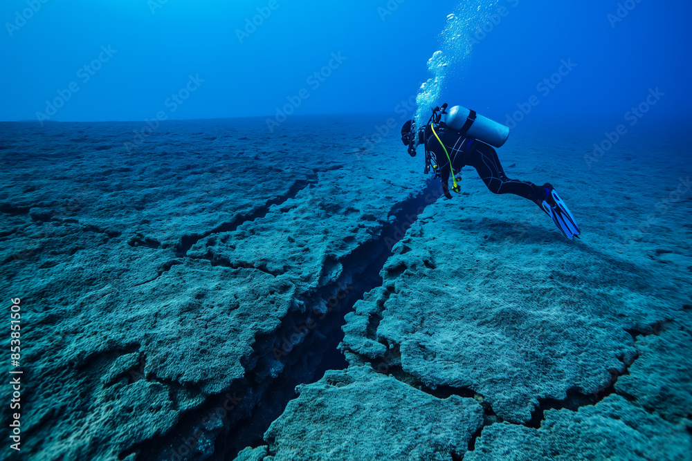 A clear underwater fault line with visible tectonic plates and a diver ...
