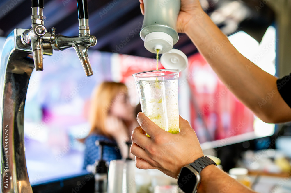 Close-up of hands pouring a drink into a clear plastic cup at an ...