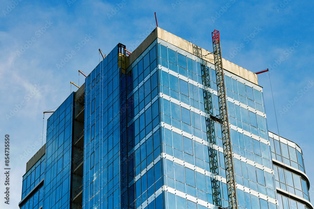 Precast glass facade panels installation, building under construction against sky background ...