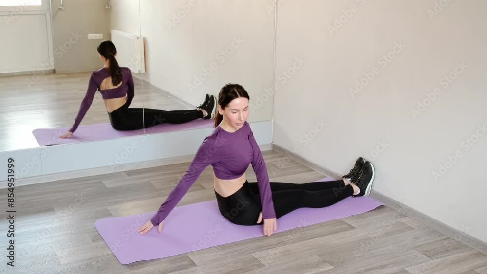 Athletic 30 year woman is doing stretching exercise rotating body to ...