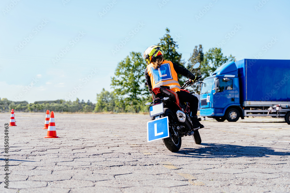 L-driver person drives slalom through the orange cones on motordrome on ...