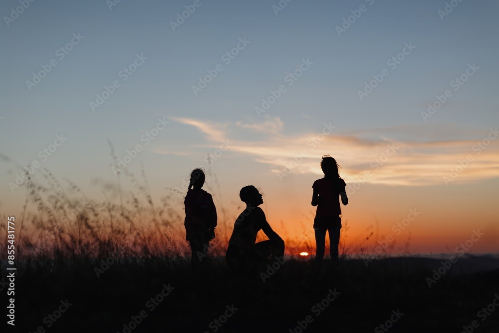 Silhouette of male ballet dancer crouching in a pose with two children ...