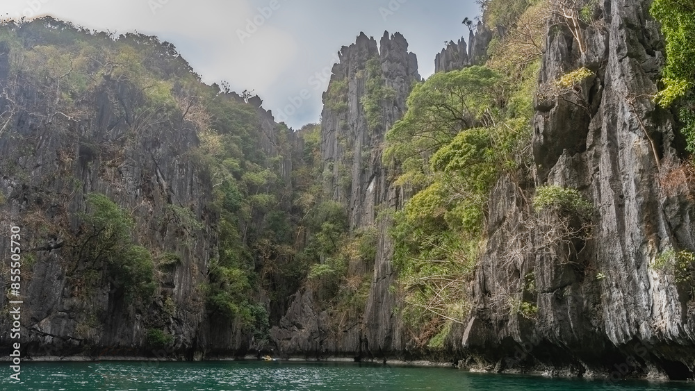 Picturesque karst rocks surround the emerald lagoon. There is green ...