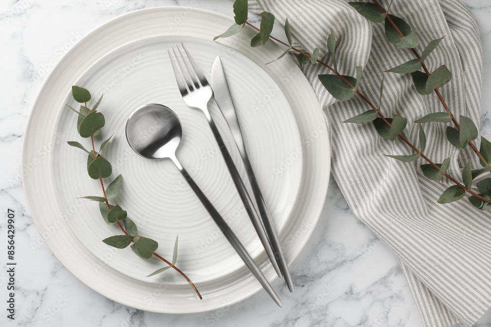 Stylish setting with cutlery, napkin, eucalyptus branches and plates on ...