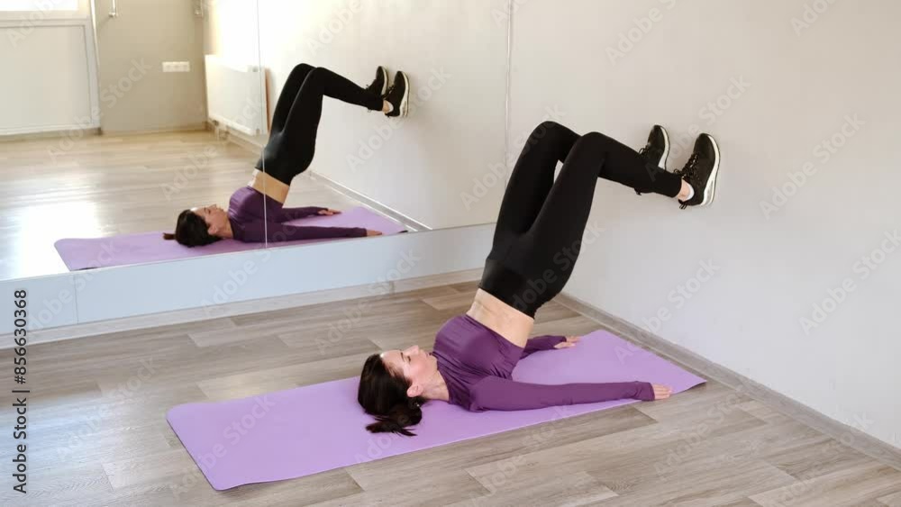 Athletic 30 year woman is doing bridge exercise raising pelvic lying on ...