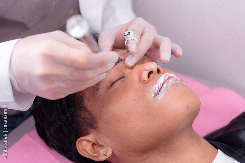A man undergoes a microblading procedure, while having topical ...
