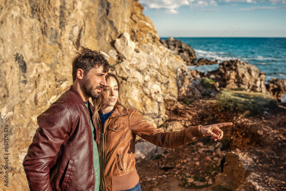 Couple exploring a scenic rocky coastline during golden hour. They are ...