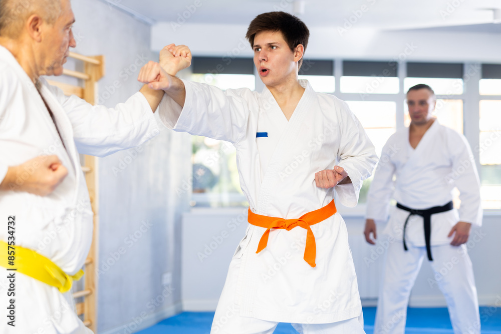 Concentrated young guy in kimono honing punching techniques during ...