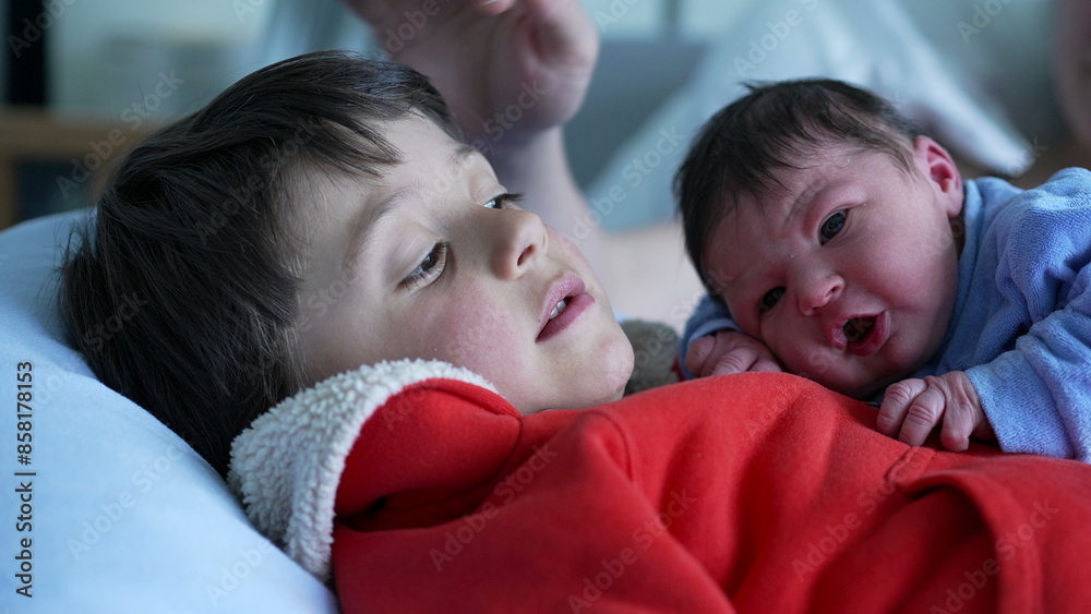 Older brother holding newborn baby close, both wearing cozy outfits ...