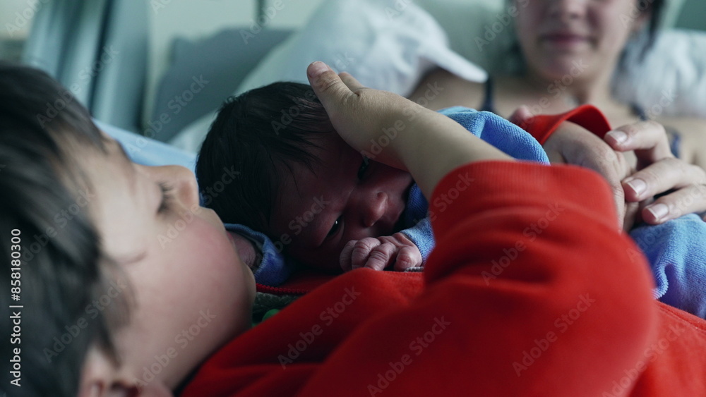 Older sibling and newborn baby cuddling together on a hospital bed ...