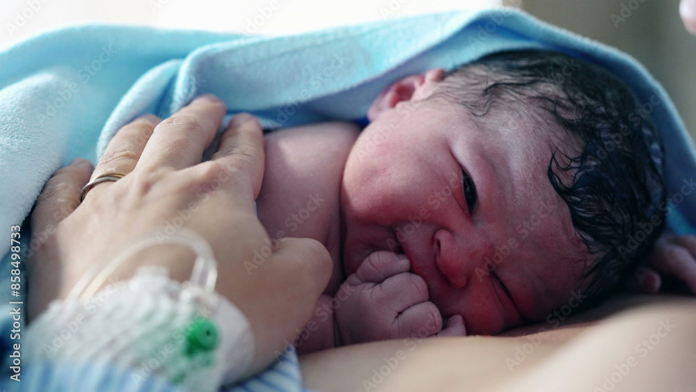 Newborn baby right after birth resting on mother's chest covered with ...