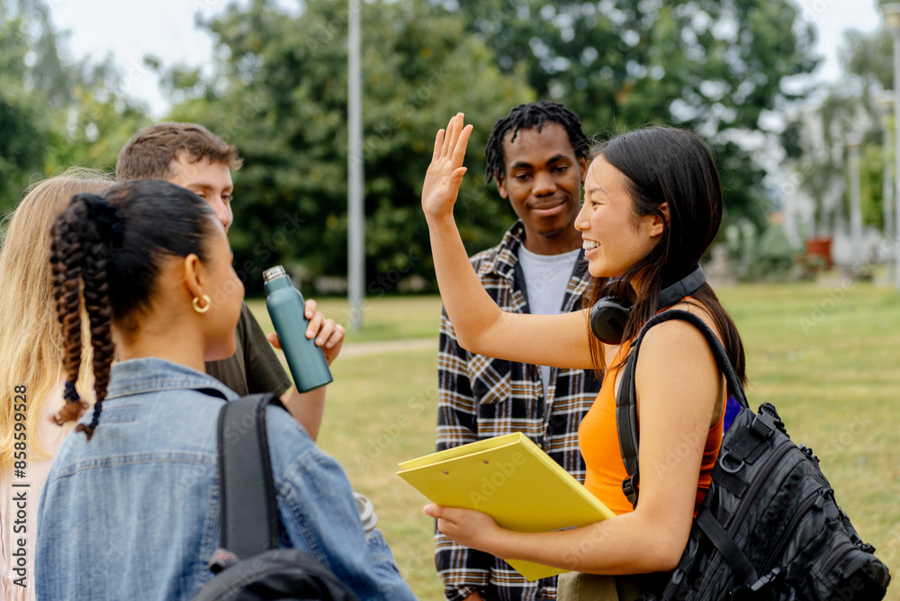 asian student high-fives her classmates upon arriving at the college or ...