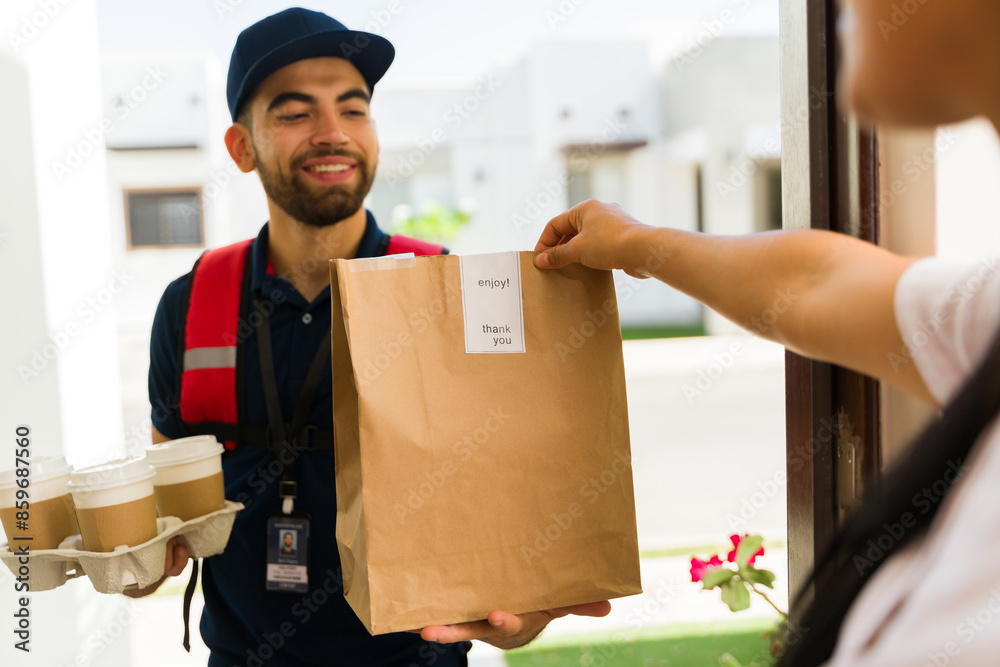 Cheerful delivery person is handing over a paper bag and a cardboard ...